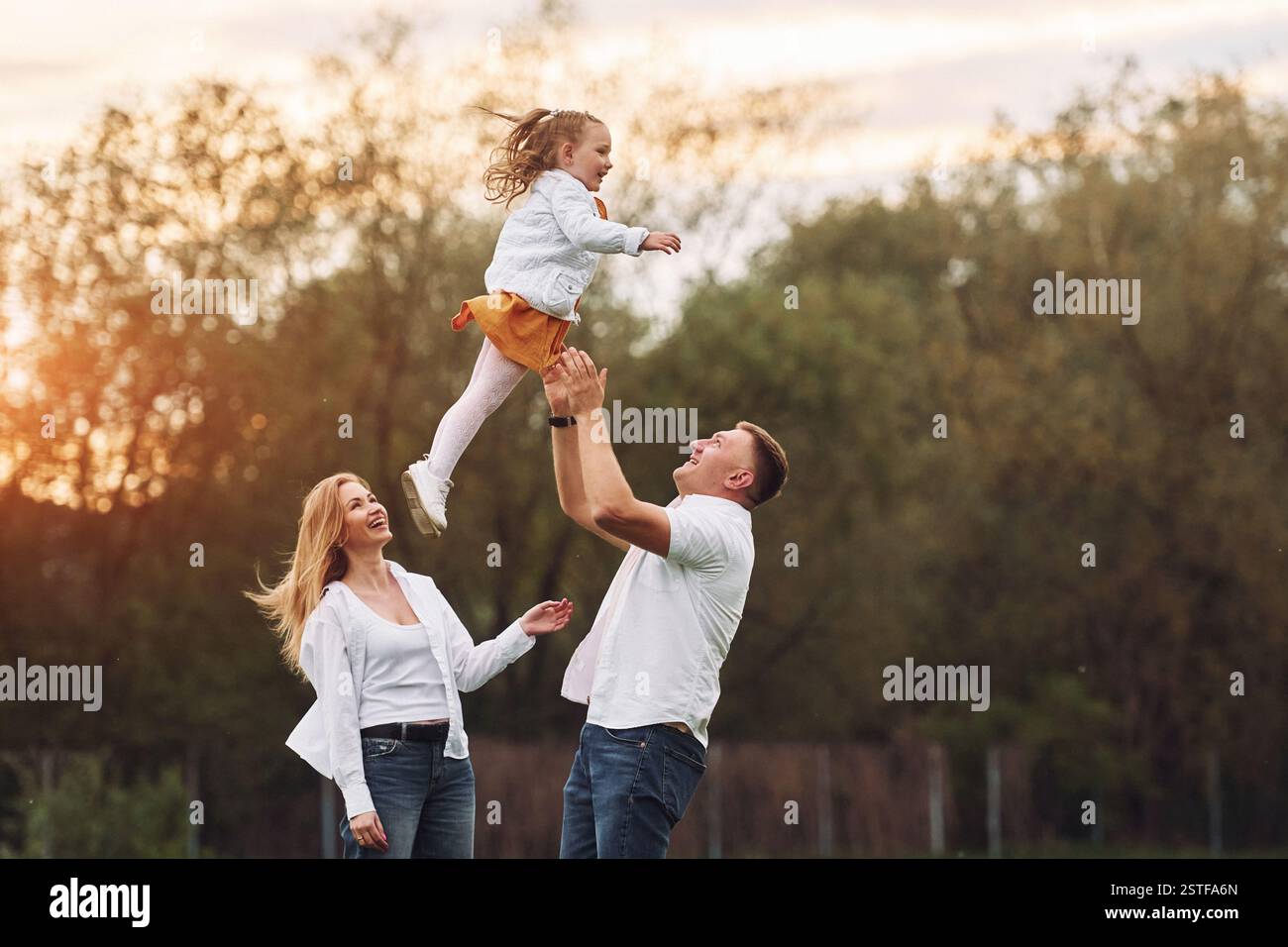 Throwing girl up and catching by the hands. Family have weekend ...