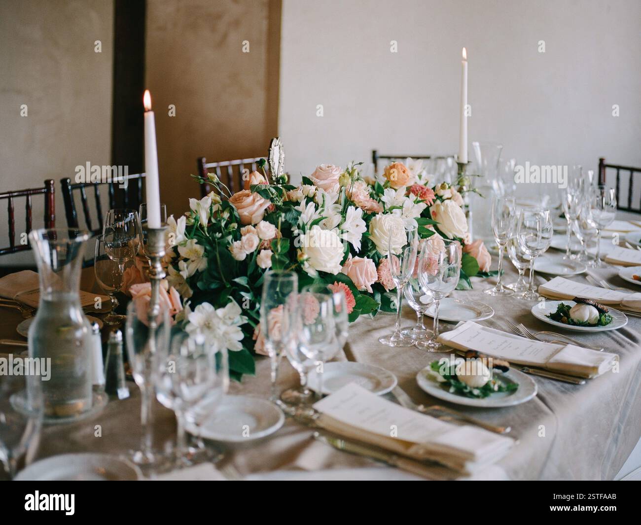 A beautifully arranged dining table features candles and fresh flowers ...