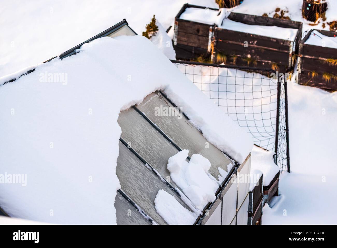 Snow-covered greenhouse roof with melting ice in winter garden ...
