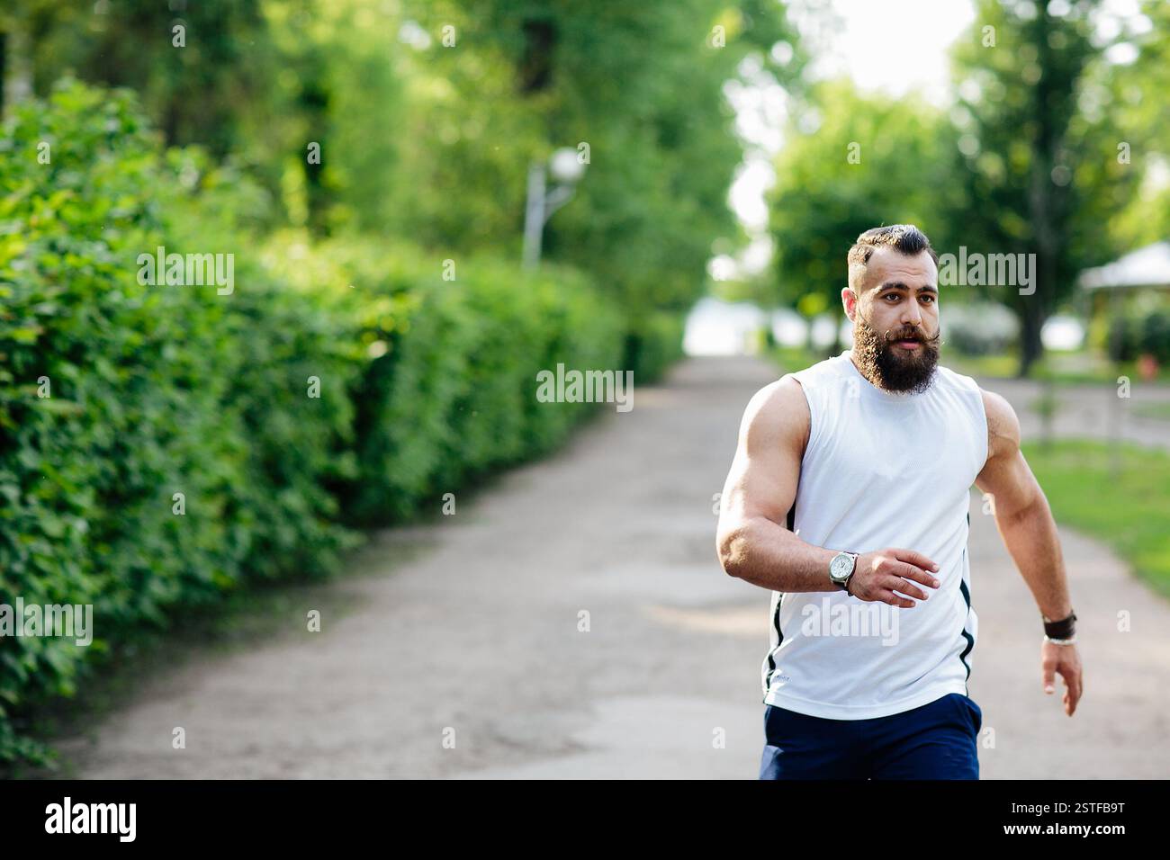 bearded man running a cross in the park at green fence Stock Photo - Alamy