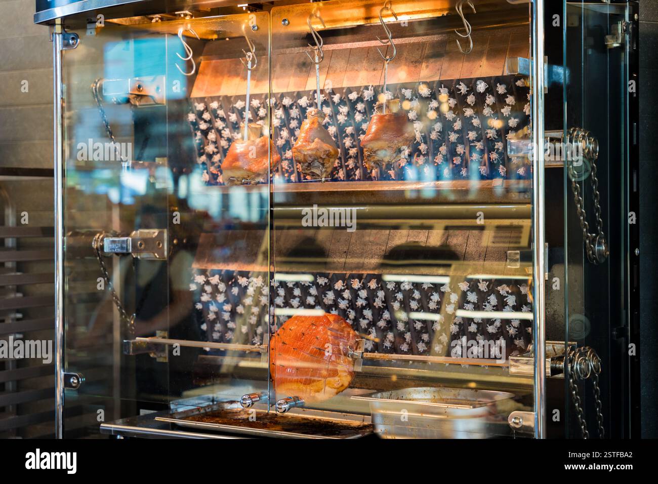 Traditional roasted pork knuckles and ham in a commercial rotisserie ...