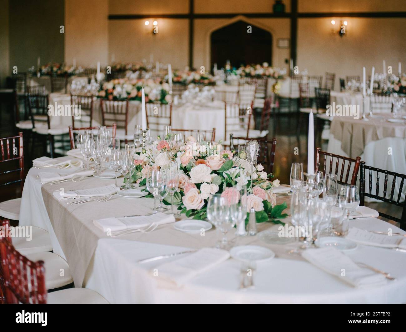 Tables are dressed in cream linens with lush floral centerpieces ...