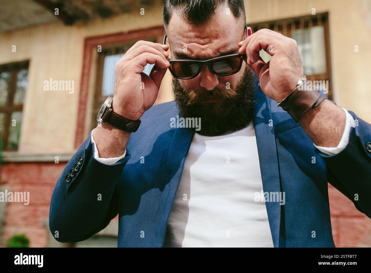 Stylish cool bearded man takes off his glasses Stock Photo - Alamy