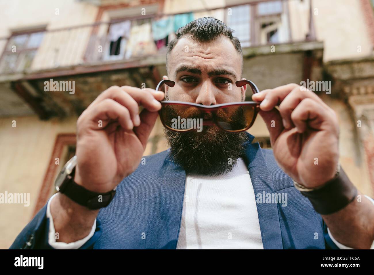 Stylish cool bearded man takes off his glasses Stock Photo - Alamy
