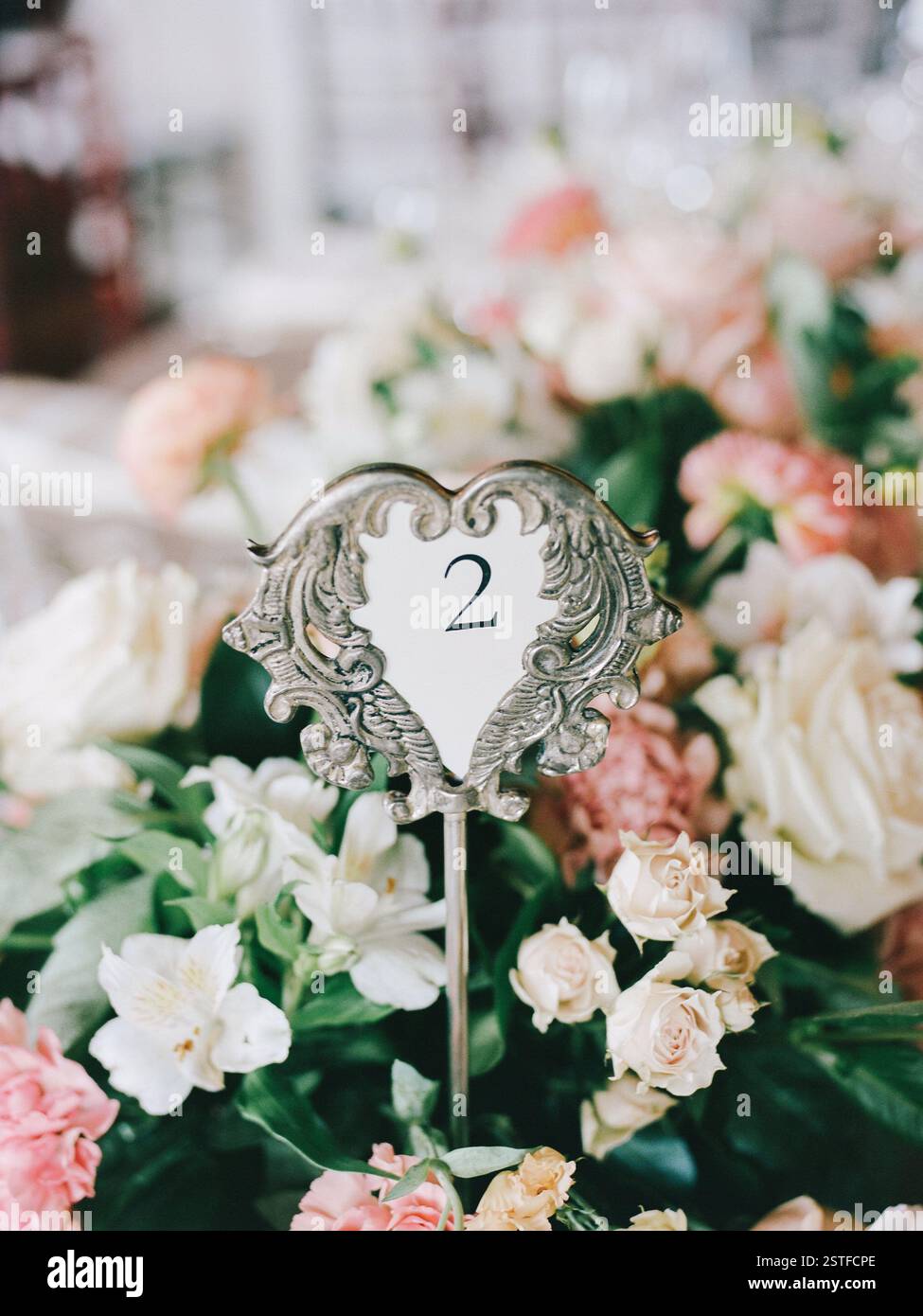 A decorative silver stand displays the number two amidst lush pink and ...