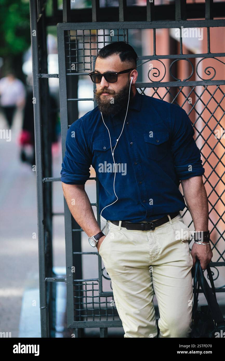 Bearded man standing and listening to music Stock Photo - Alamy