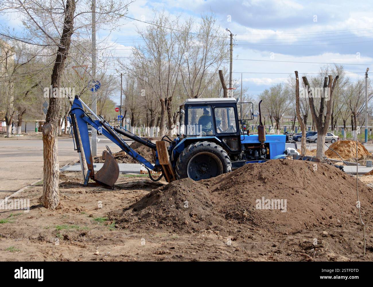 Excavator painted in blue color side view digging earth Stock Photo - Alamy