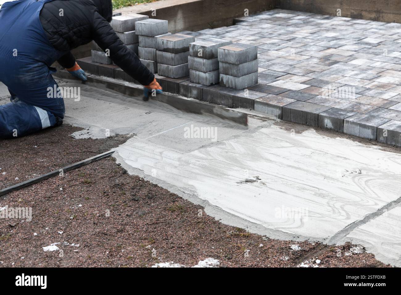 Worker installs paving bricks for an outdoor pathway, ensuring a stable ...