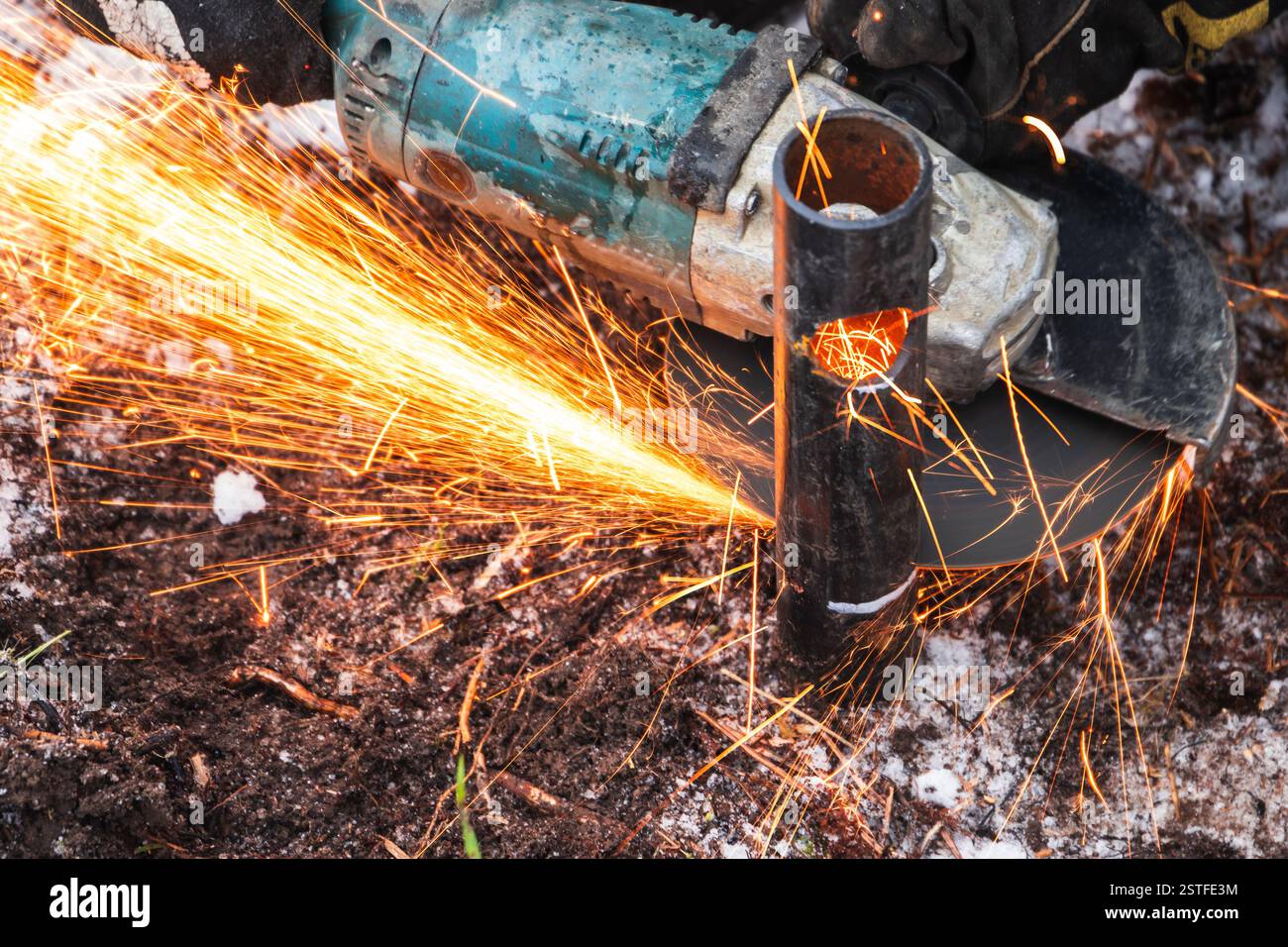 Angle grinder in action cutting through a metal pipe, emitting bright ...