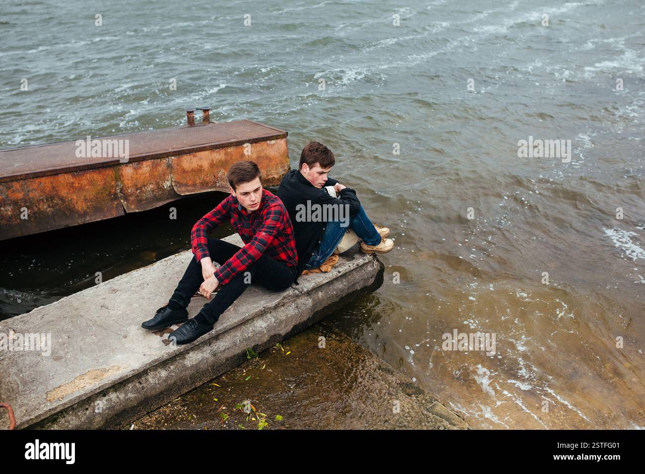 Two friends relaxing on a pier in the background water Stock Photo - Alamy
