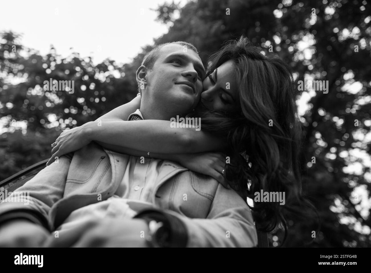 Young European couple cuddling on a park bench Stock Photo - Alamy