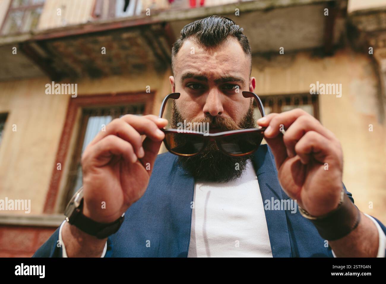 Stylish cool bearded man takes off his glasses Stock Photo - Alamy