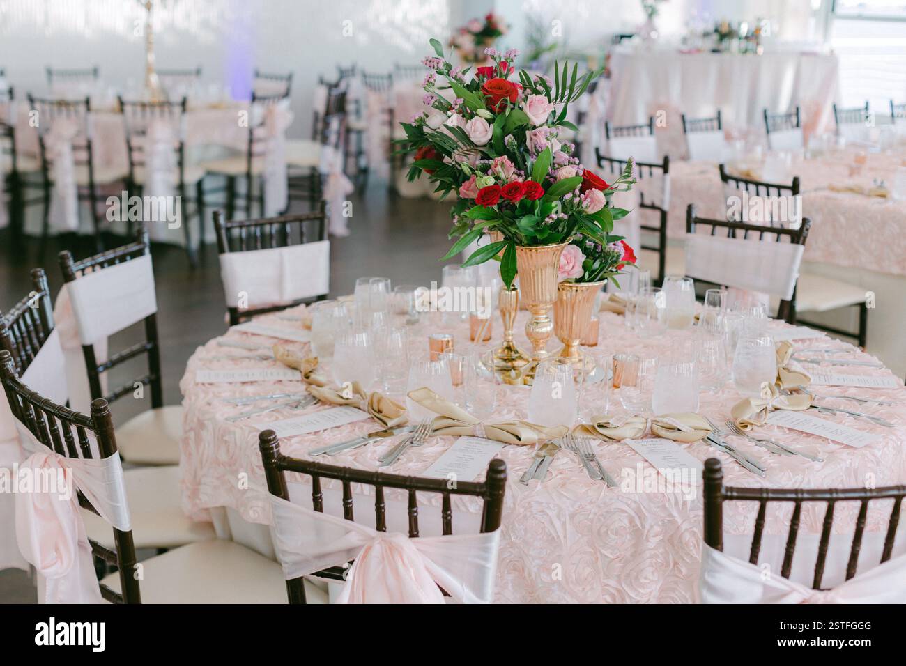 A beautifully arranged table features a vibrant floral centerpiece, set ...