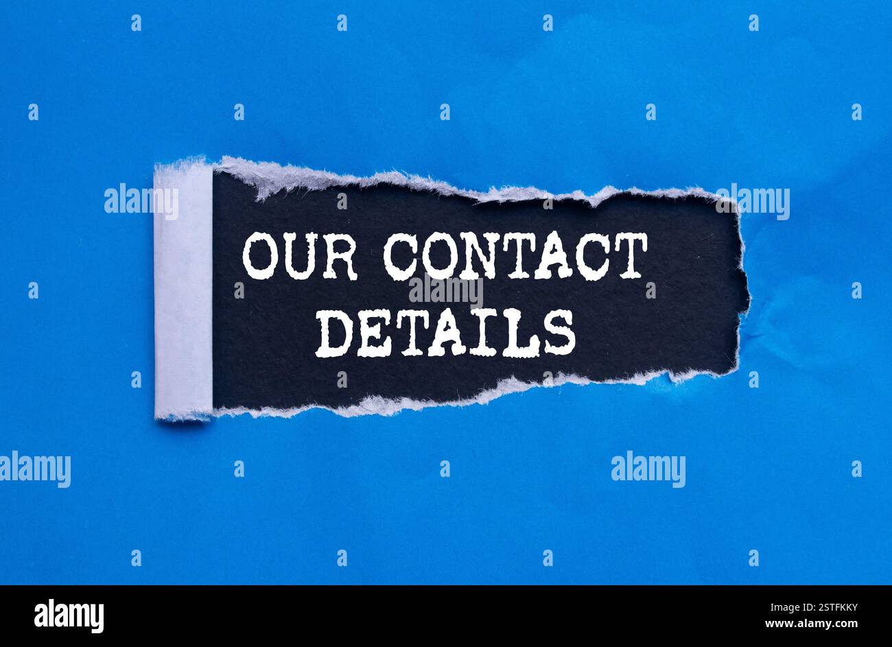 Our contact details message written on ripped torn blue paper on black background. Conceptual ...