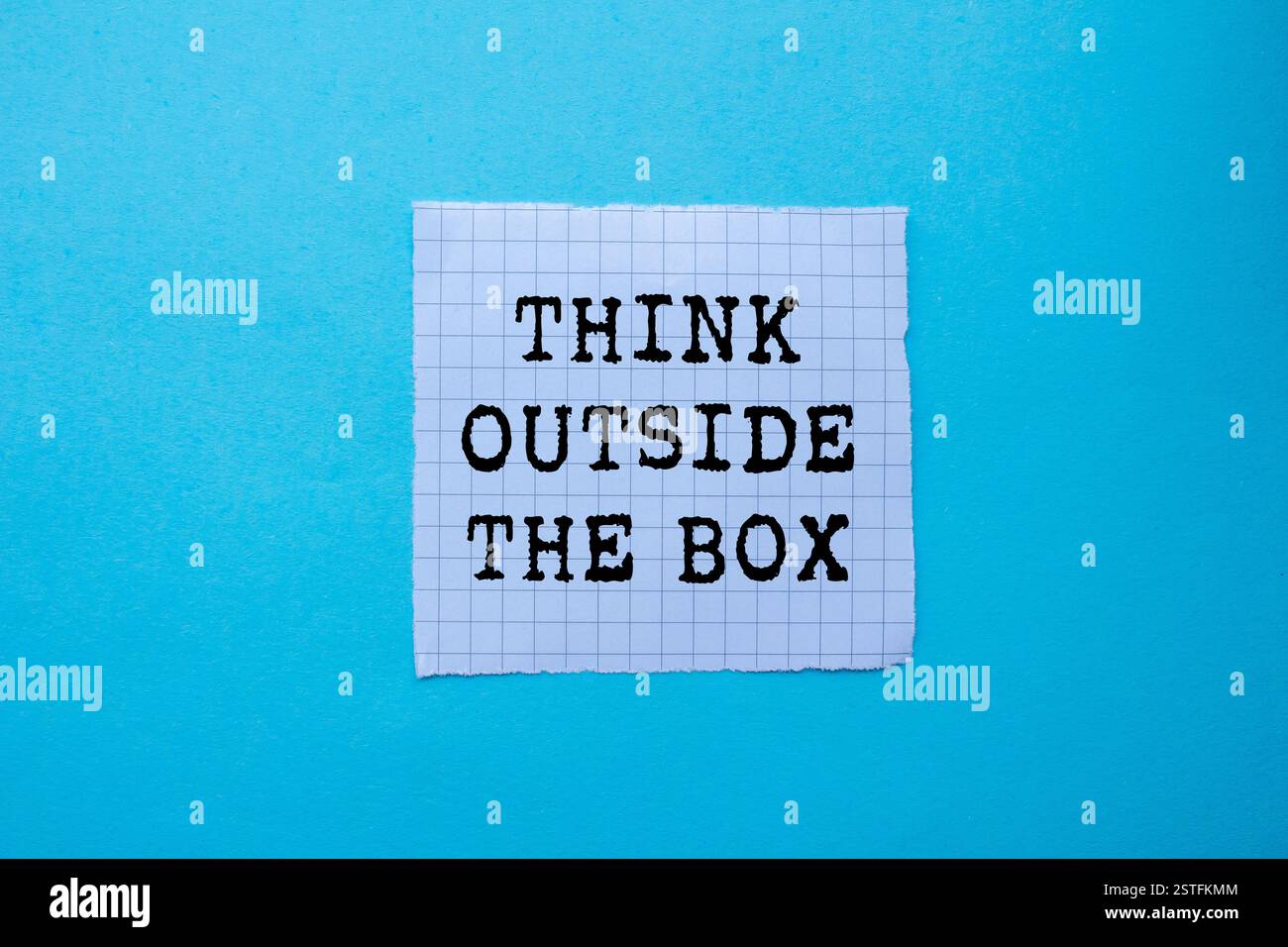 Think outside the box message written on ripped torn white paper on blue background. Conceptual ...