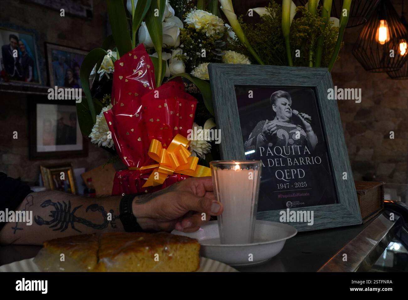 Storeowner Carlos Torres places a candle alongside a tribute to the ...