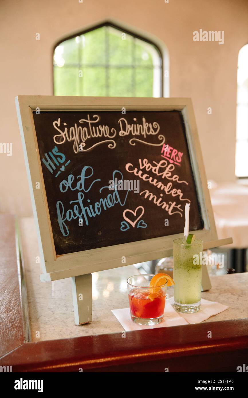 A chalkboard displays two signature cocktails, an old fashioned and a ...