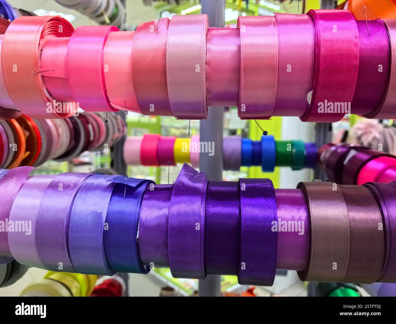 Colorful spools of ribbons hang invitingly in a craft store, showcasing ...