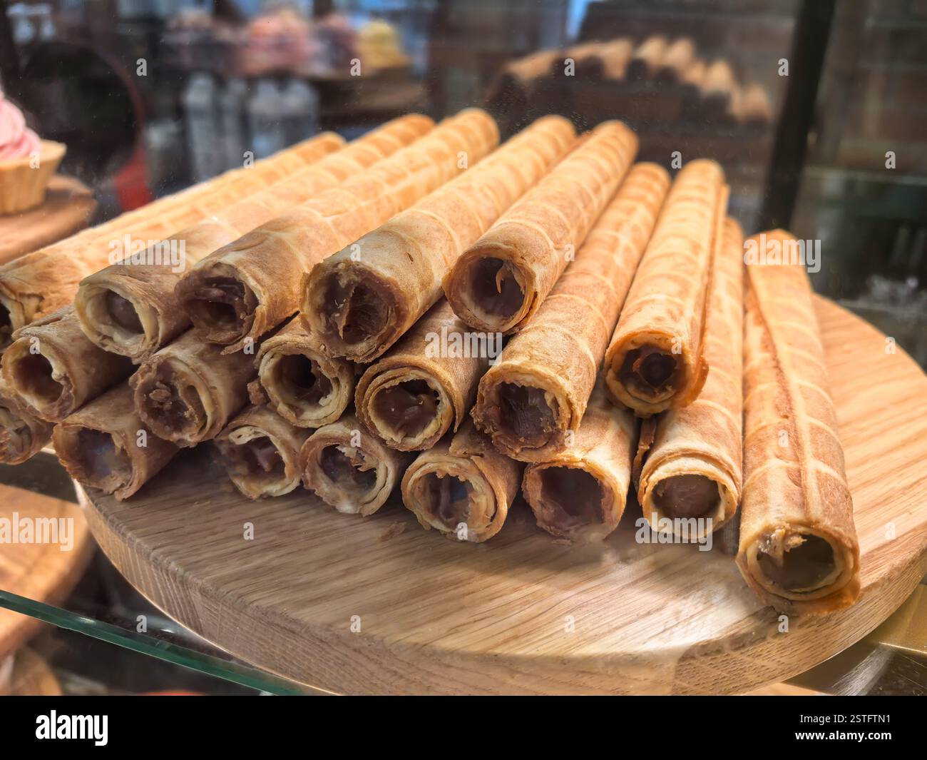 Rows of golden, crispy pastries sit invitingly on a wooden display ...