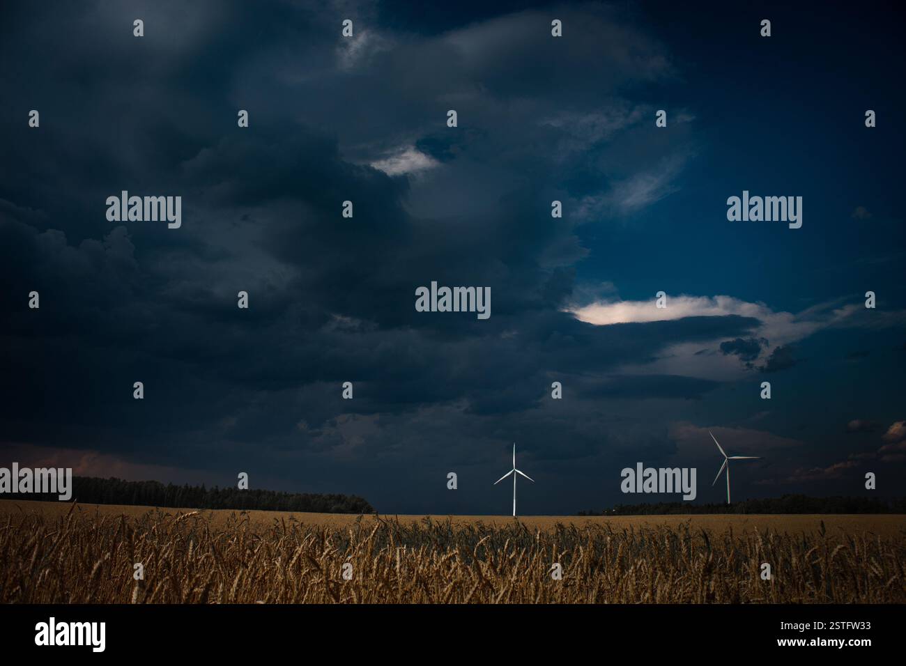 A dramatic landscape featuring dark storm clouds rolling over a golden ...