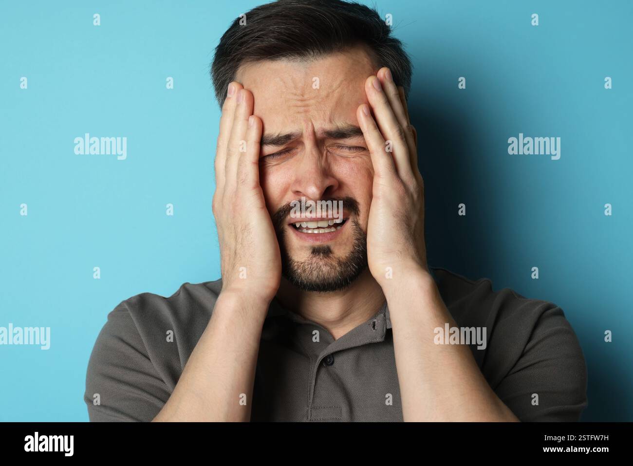 Sad man crying on light blue background Stock Photo - Alamy