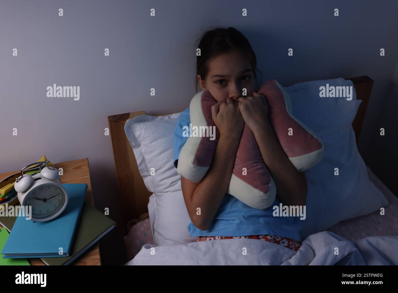 Afraid girl with pillow in bed at night Stock Photo - Alamy