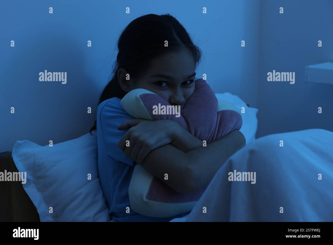 Afraid girl with pillow in bed at night Stock Photo - Alamy