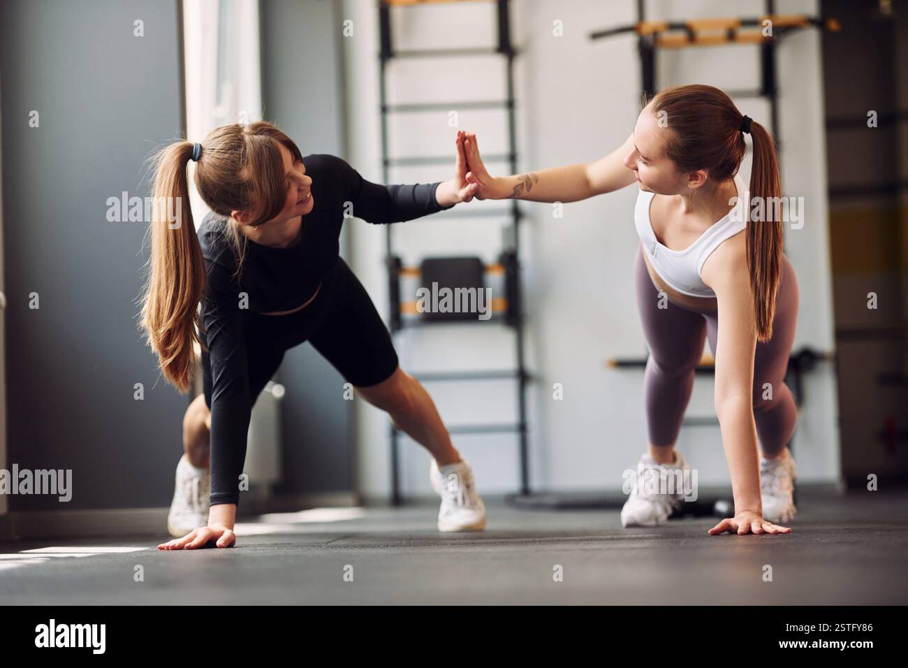 Doing push ups and giving high five. Two women in sportive clothes have ...