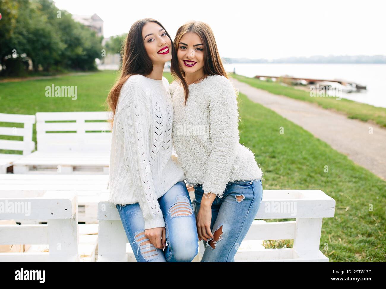 Two girls lean bench Stock Photo - Alamy