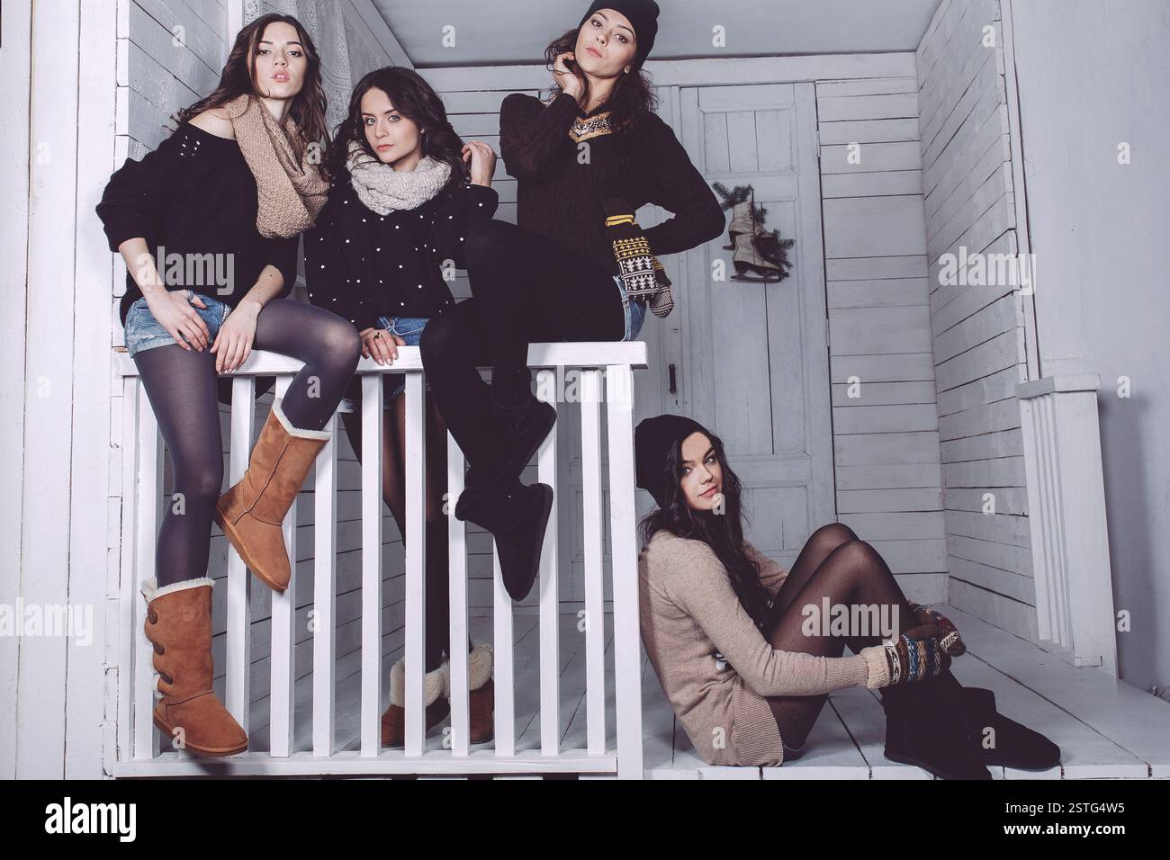 Four stylish models posing sitting on the fence Stock Photo - Alamy