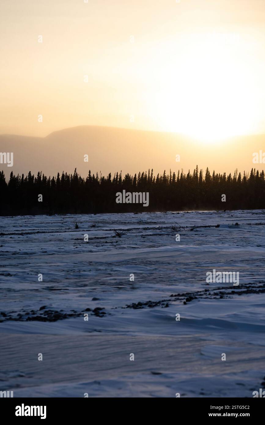 Sun rising over mountains behind frozen river on the winter solstice in ...
