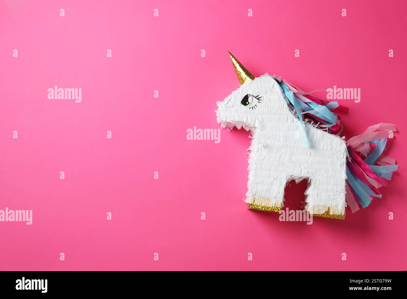 Bright pinata in shape of unicorn on pink background, top view. Space ...