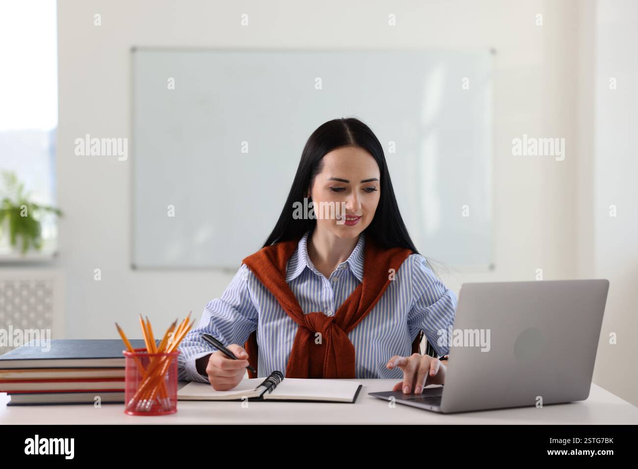 English teacher working at desk in classroom Stock Photo - Alamy