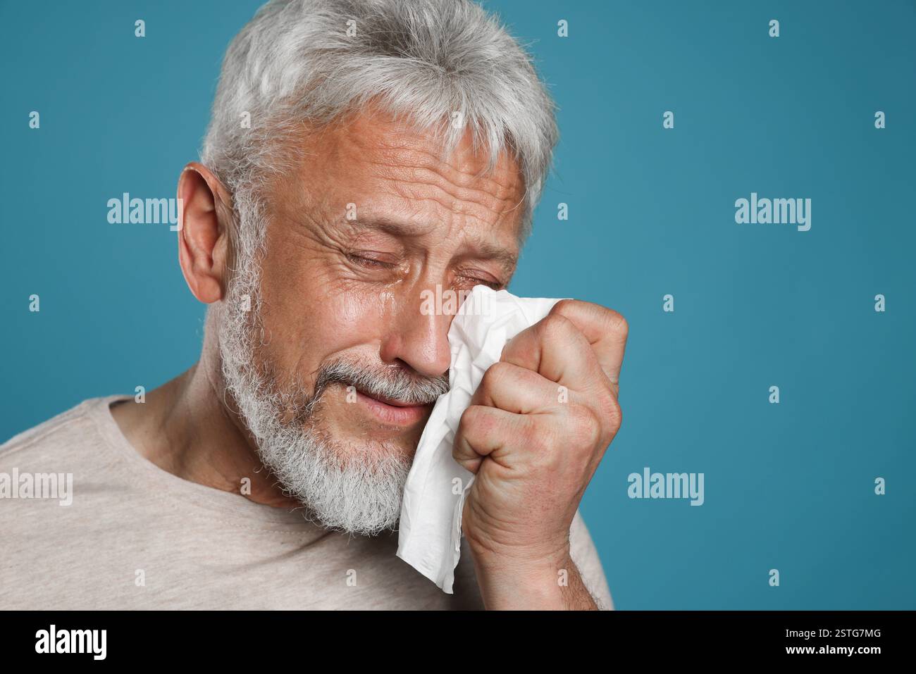Sad senior man crying on light blue background Stock Photo - Alamy