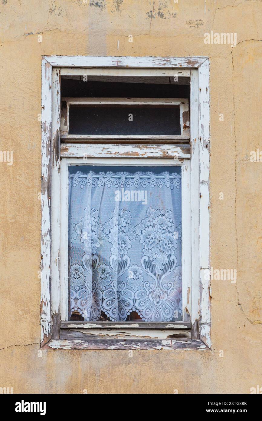 window with flower decoration in the curtain and rotten wooden window ...