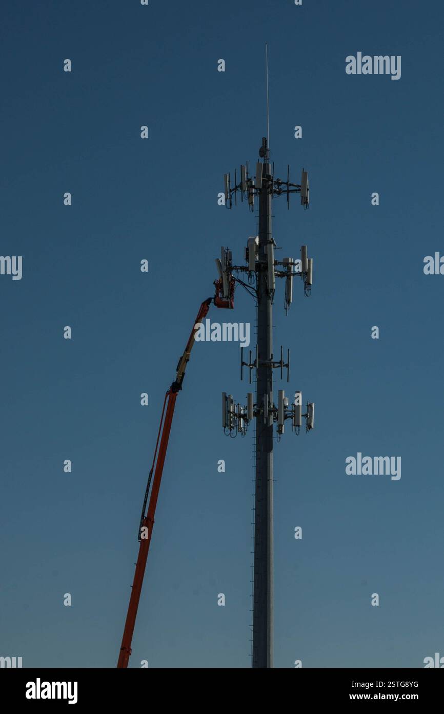 Workers make repairs and maintenance on a cellular phone tower using a ...