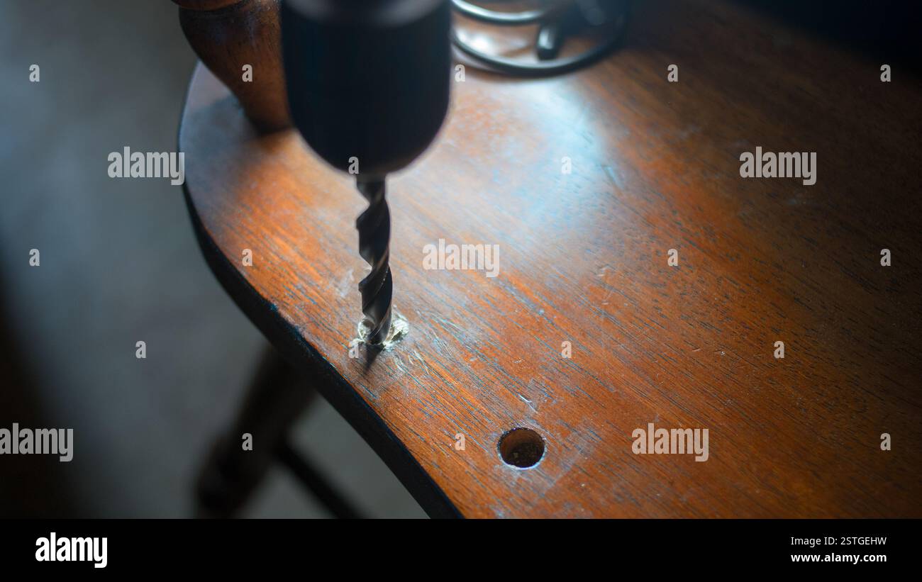 Drilling. Carpenter repairing old chair Stock Photo - Alamy