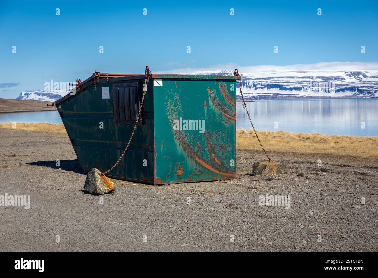 Large, steel waste container attached to the ground with chains and ...