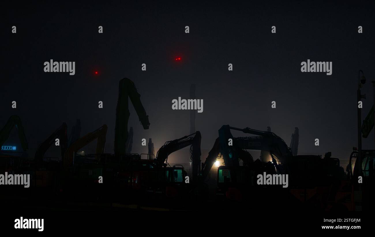 Diggers silhouetted in an industrial zone on a misty night Stock Photo ...