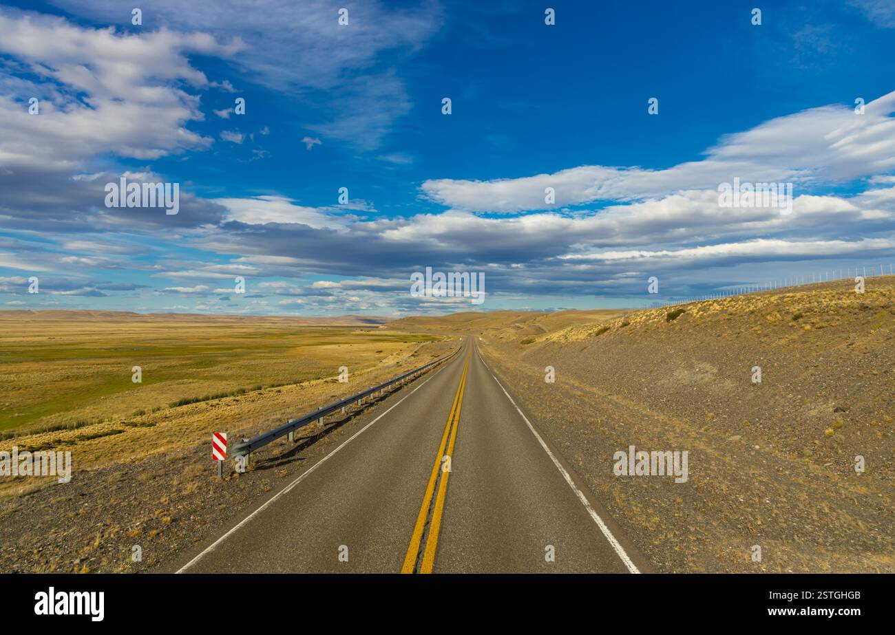 A long, empty road stretches endlessly through a vast, arid landscape ...