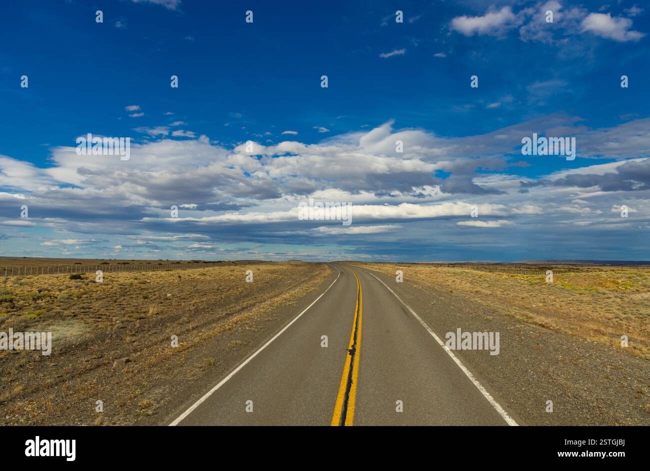 A long, empty road stretches endlessly through a vast, arid landscape ...