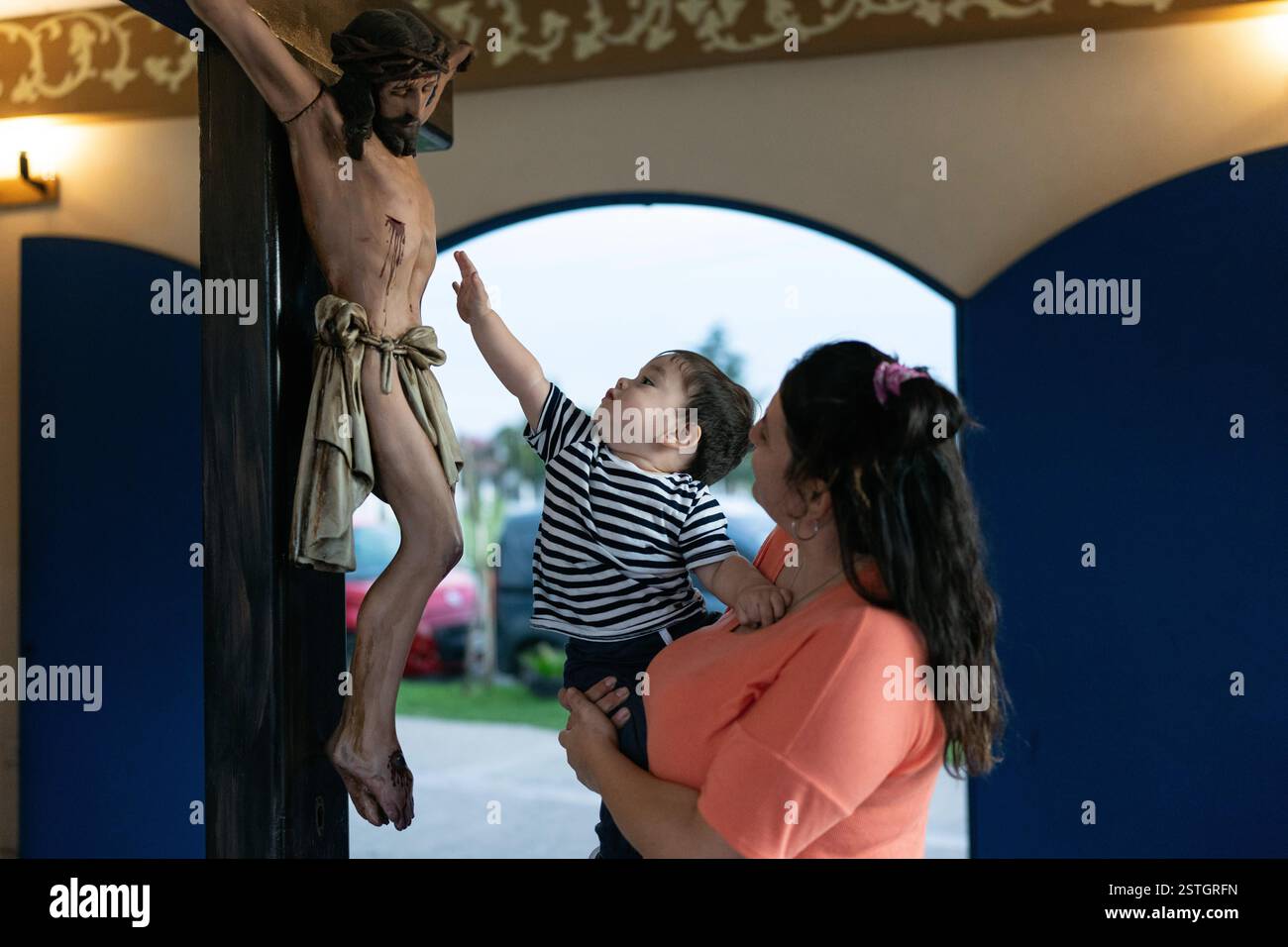 Milo Montiel tries to touch an image of Jesus Christ while being held ...