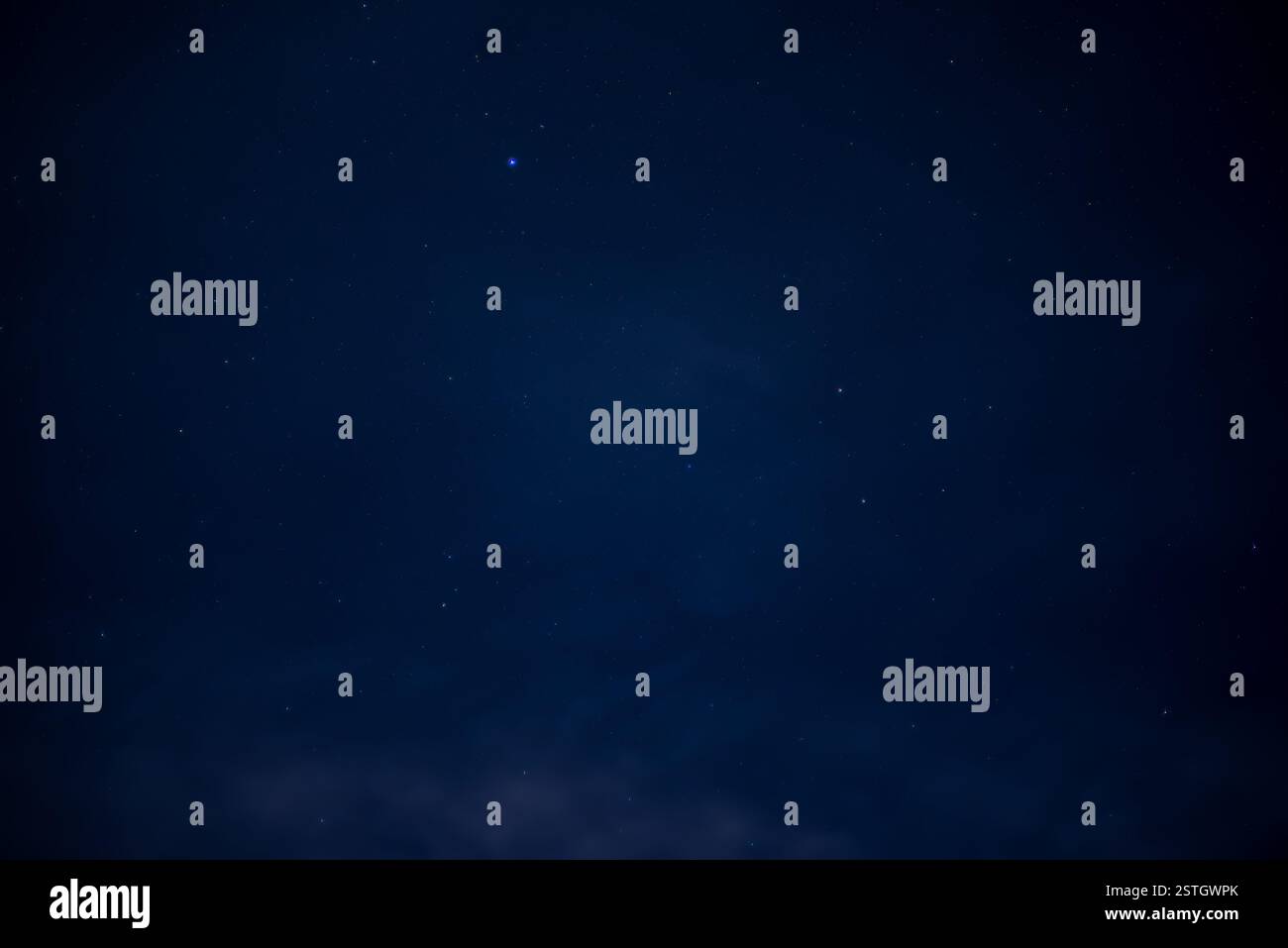 A deep blue night sky filled with stars and faint clouds, creating a ...