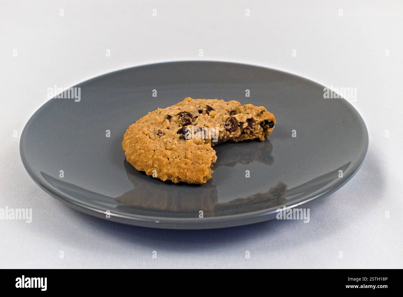 A single delicious oatmeal cookie with a bite taken out of it on a gray ...
