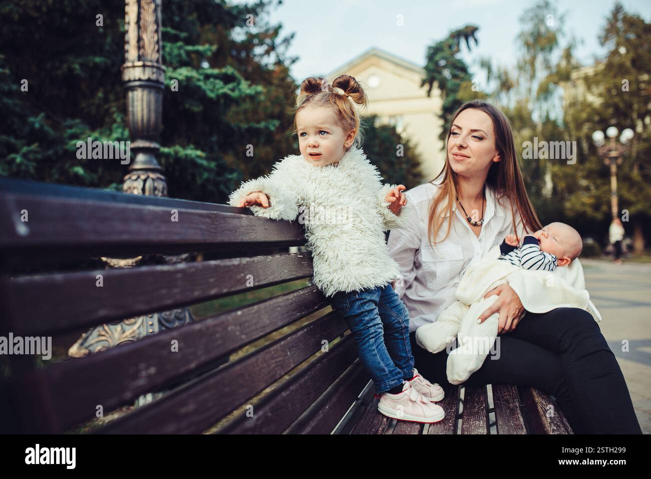 Mother and two daughters rest on a bench Stock Photo - Alamy