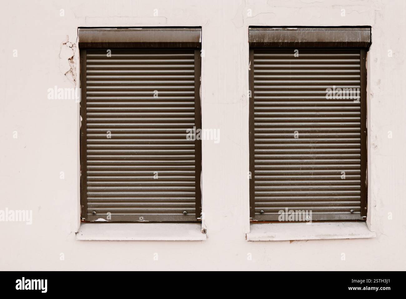 Wall with two closed by roller-blind windows Stock Photo - Alamy
