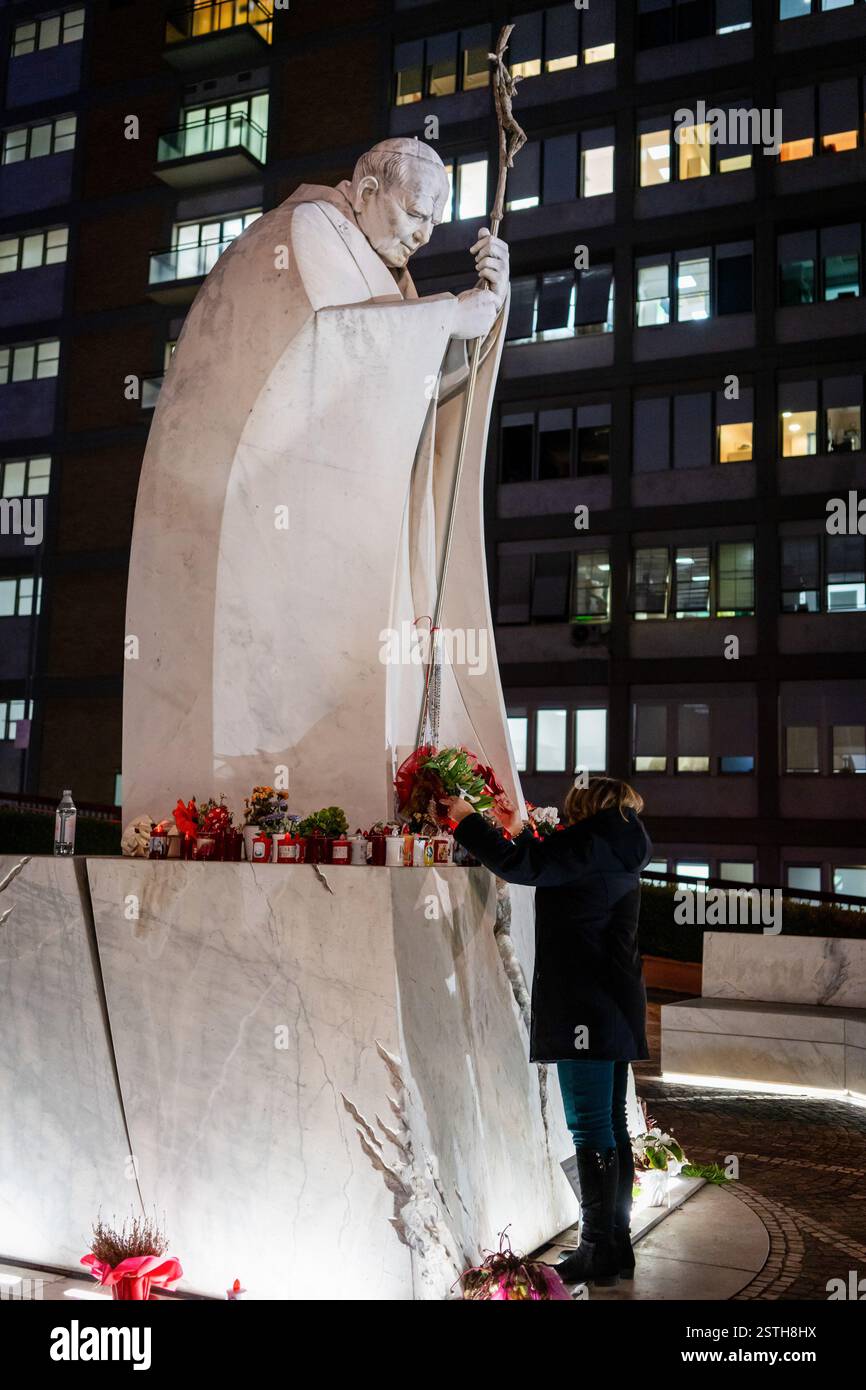 Rome, Italy. 18th Feb, 2025. A woman carries flowers under the statue ...
