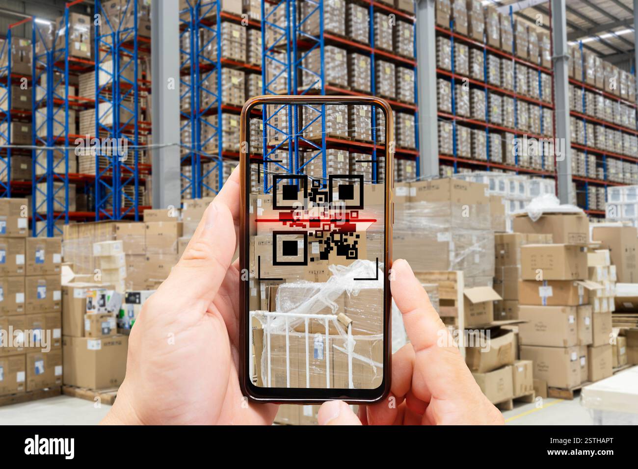Person scanning QR code on smartphone in a warehouse with stacked boxes ...