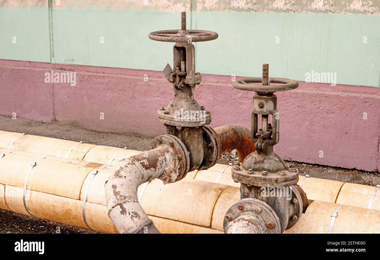 Two old rusty hot water valves onpipes outdoors Stock Photo - Alamy