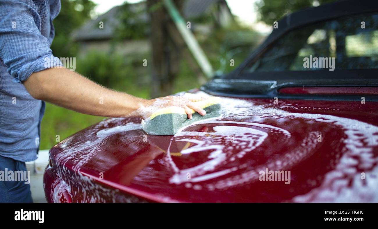Hand washing a red car with soapy sponge in outdoor setting Stock Photo ...